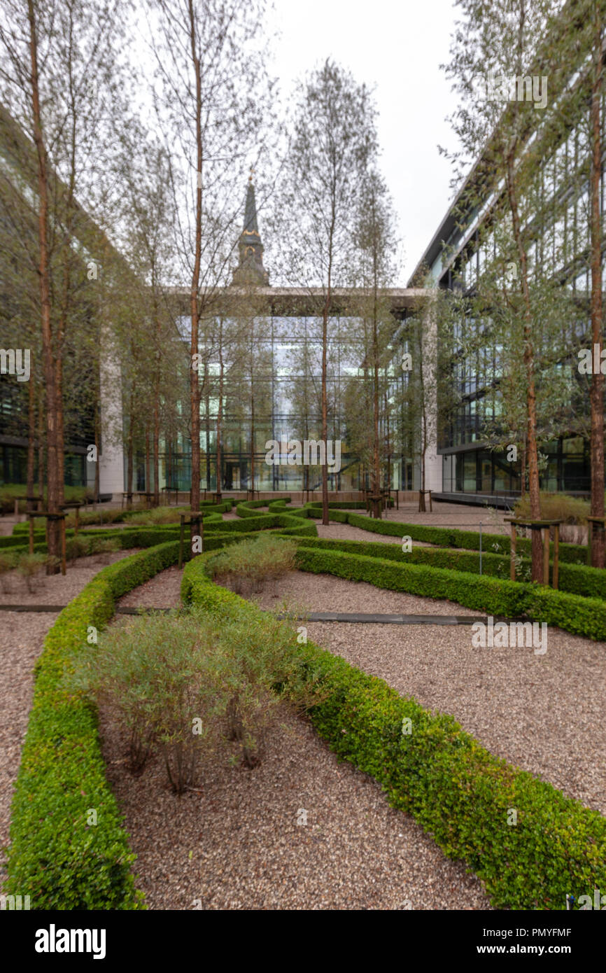 Modern office building, in U shape, with a garden with tress in the ...