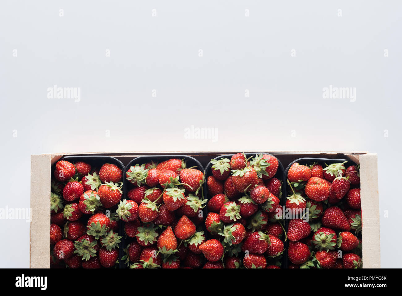 top view of box of plastic containers with ripe strawberries on white ...