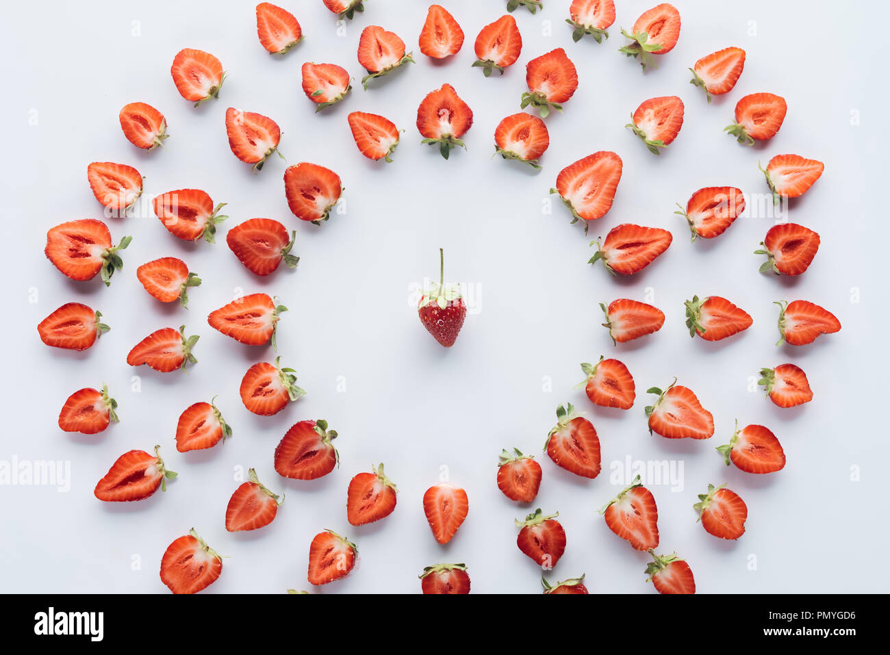 top view of round frame of halved strawberries with whole in middle on ...