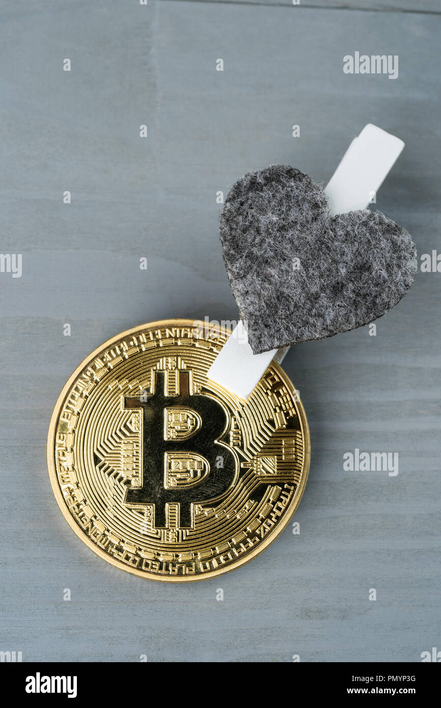 Gold physical Bitcoin coin with heart clip on grey background. Crypto ...