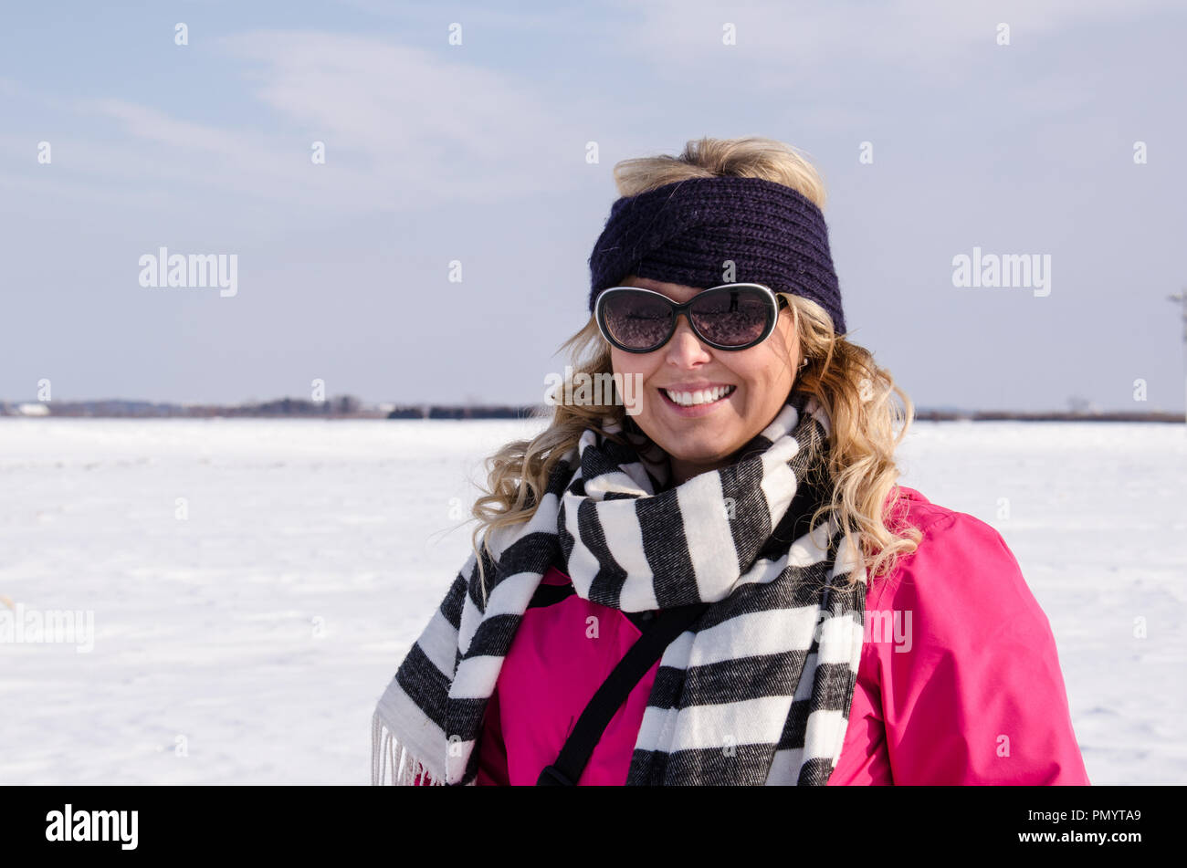 Attractive adult woman poses in farm field covered in snow on a cold ...