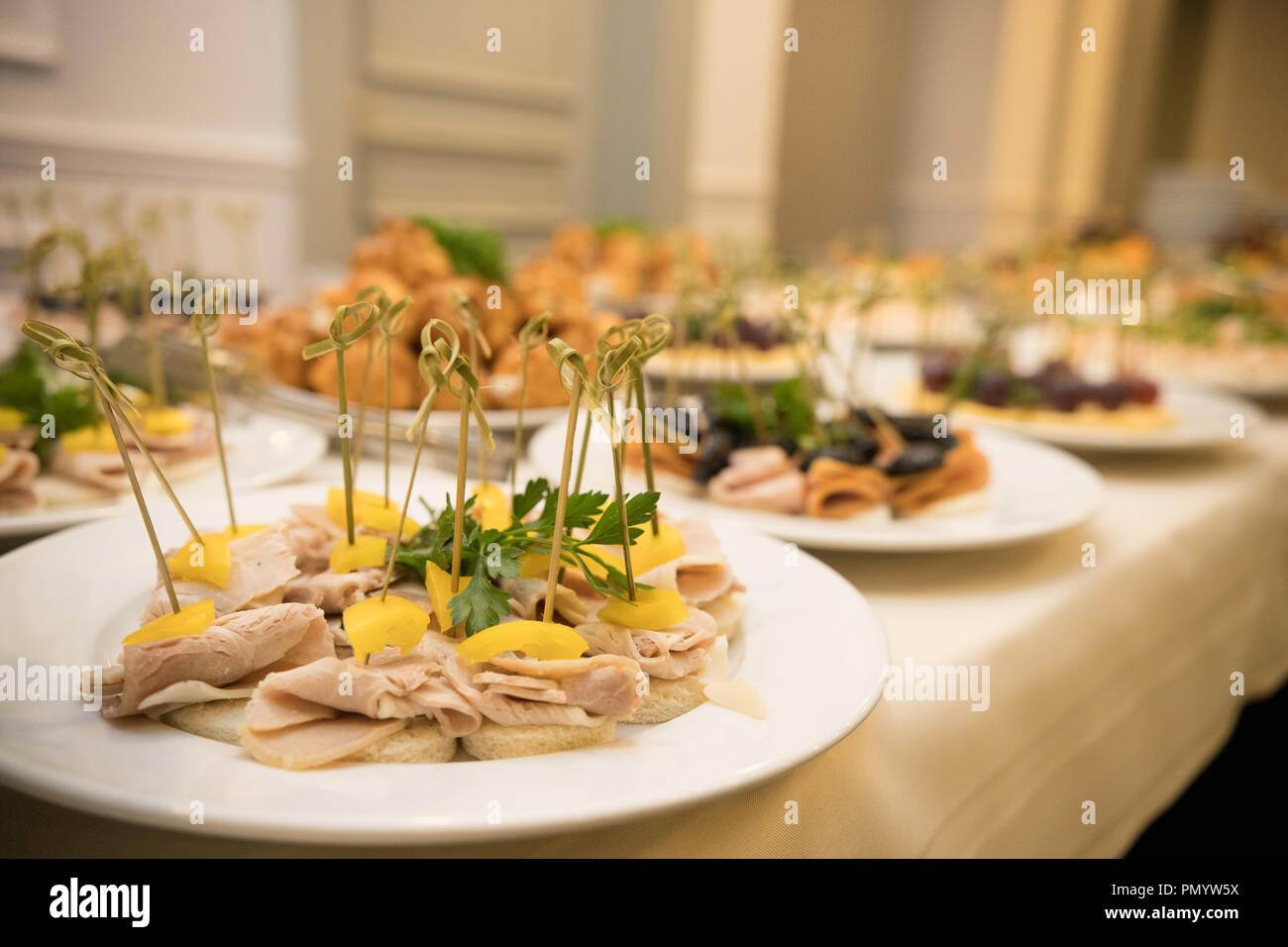 Row of plates with various cold appetizers standing on a table with a ...