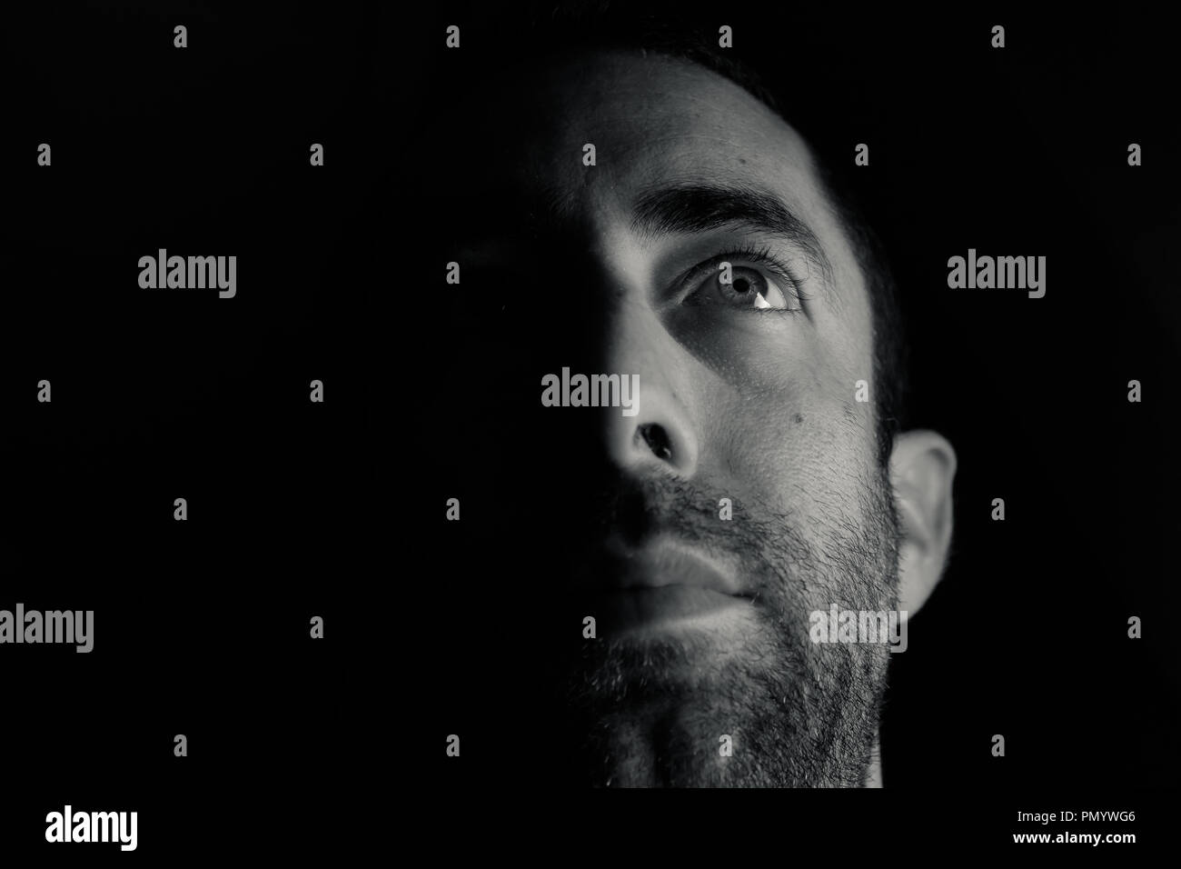 Dramatic portrait of a young man half expressionless face in deep ...