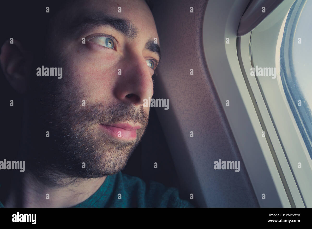 Close up of a pensive man looking outside through the window of an ...