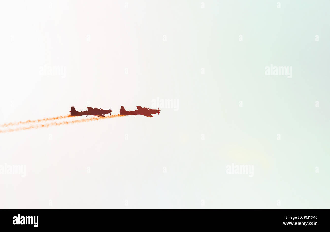 Silhouette of two airplanes flying together leaving a smoke trail ...