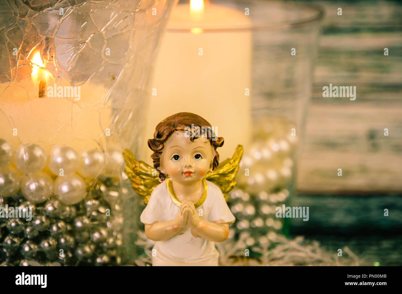praying angel figure and two festive burning candles Stock Photo - Alamy