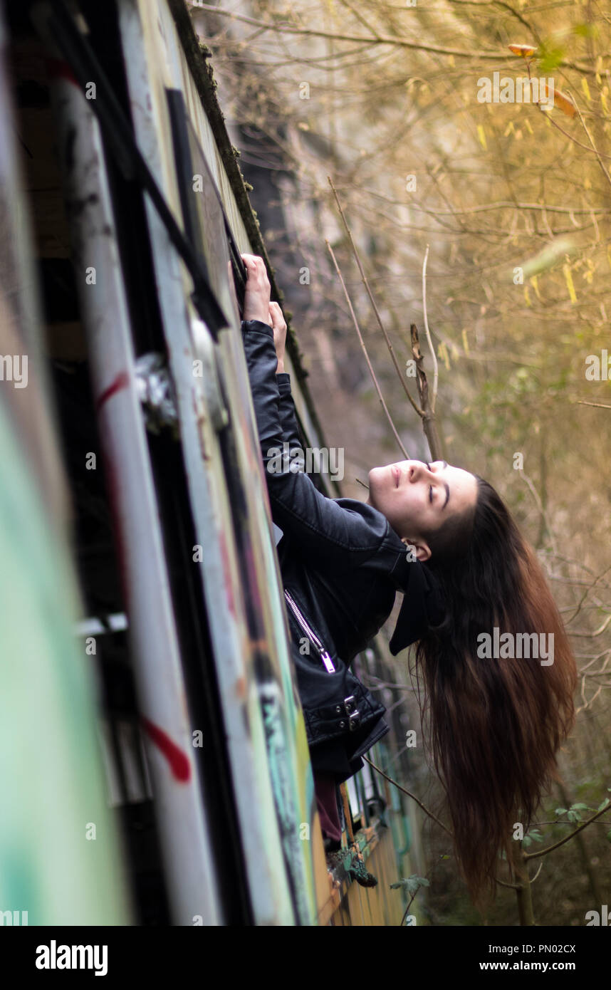 Young brunette woman hanging out of an abandoned train window in the ...