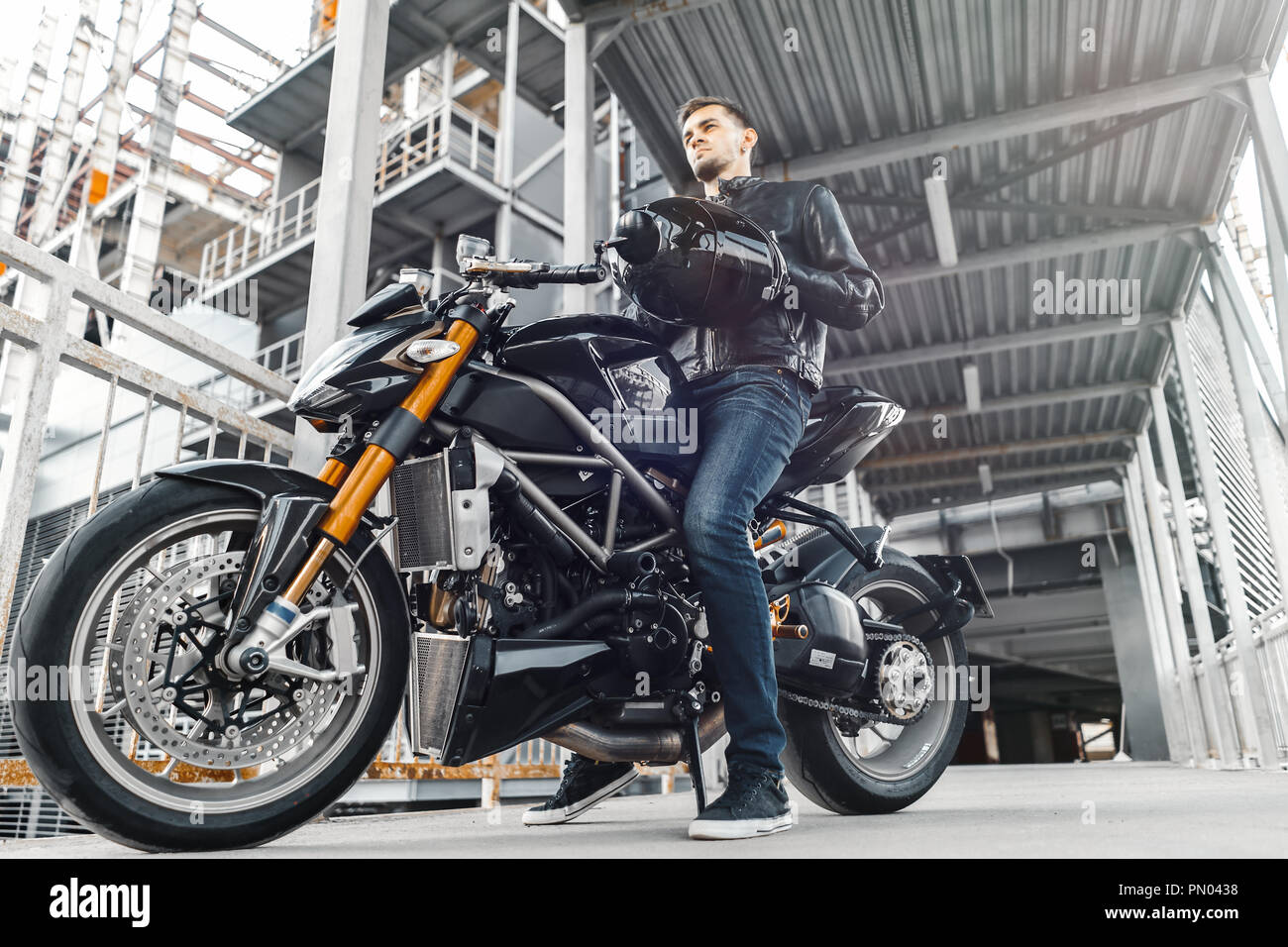 Handsome biker sitting on motorcycle and putting on helmet Stock Photo ...