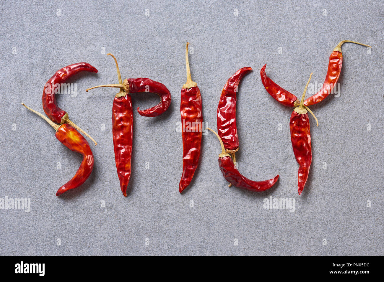 top view of dried chili peppers arranged in spicy lettering on grey ...