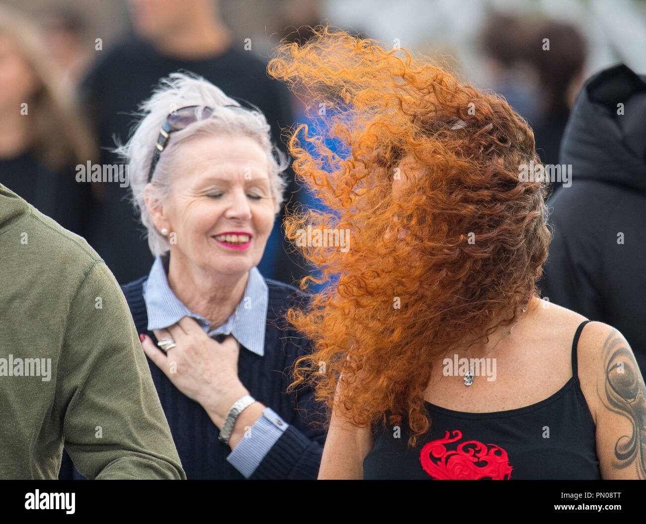 People experience strong winds as they cross the Millennium Bridge, in ...