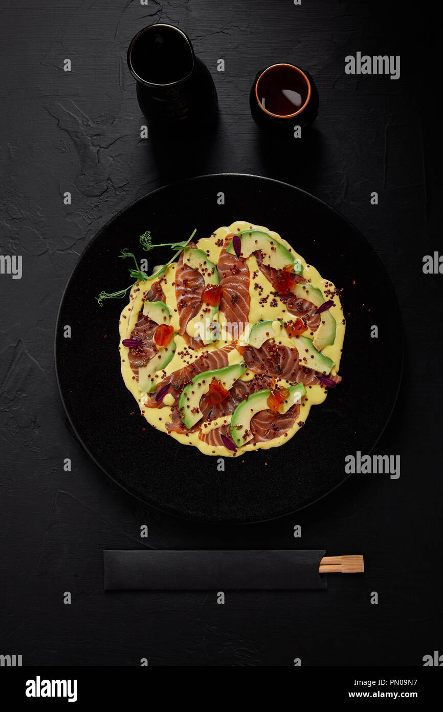 top view of gourmet japanese dish with sliced fish and avocado in sauce ...