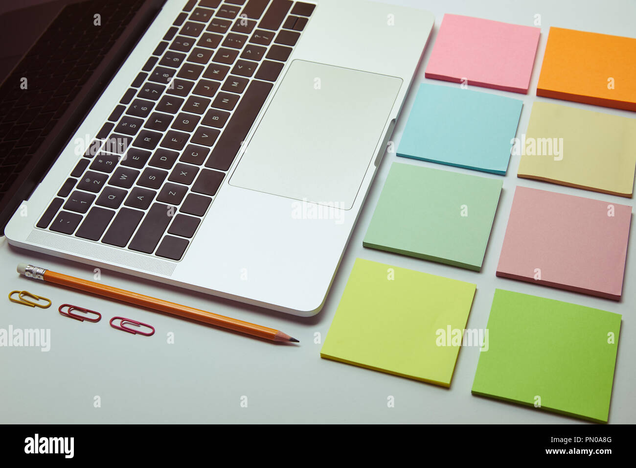 laptop, set of paper stickers, pencil and paper clips on white tabletop ...