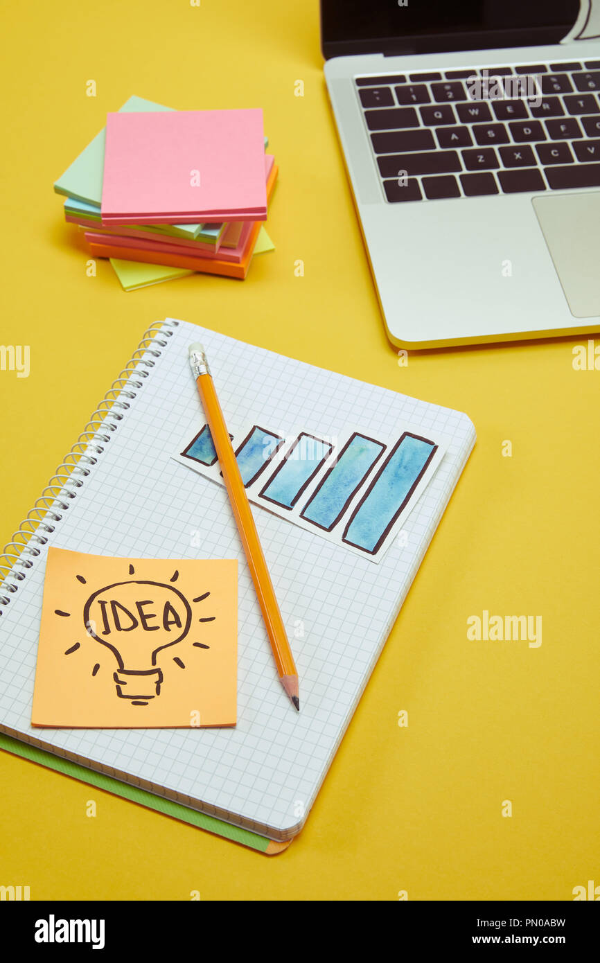 laptop, notebook, pencil chart sign and idea sign on wooden tabletop ...