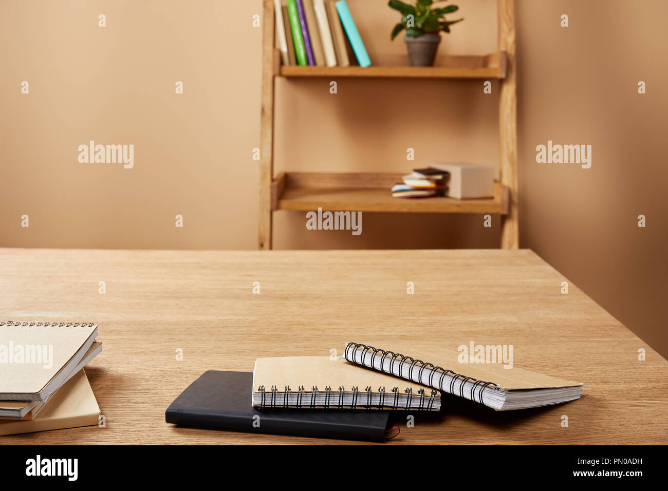 notebooks on wooden table, shelves with books and plant at home Stock ...