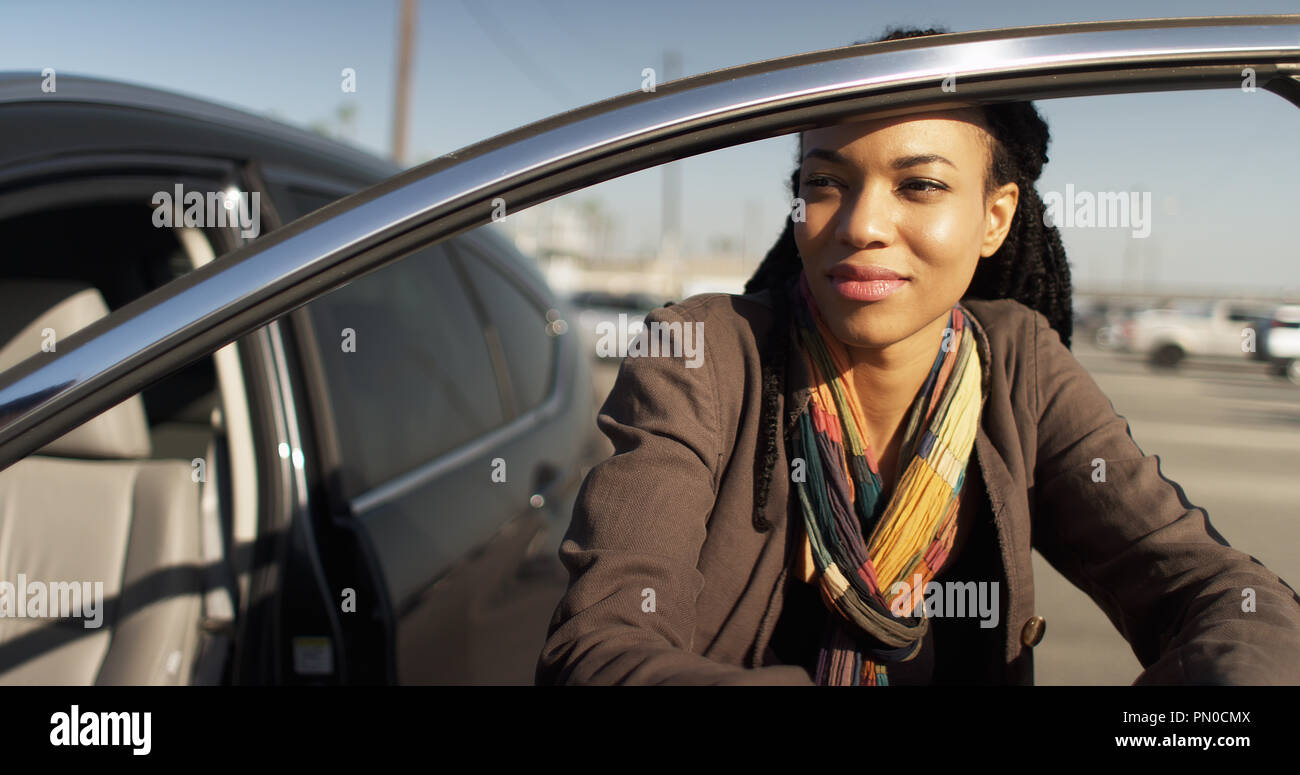 Black woman leaning against car door in parking lot Stock Photo - Alamy