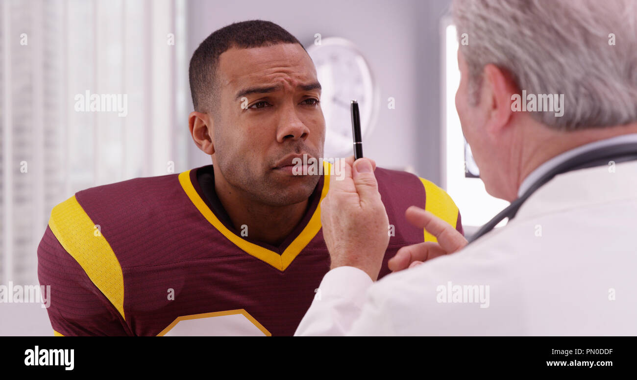 Portrait of handsome football player consulting sports injury with a ...
