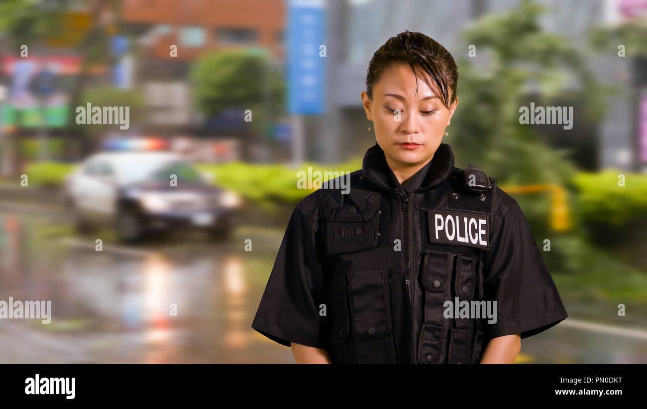 Asian American Woman Police Officer looking down Stock Photo - Alamy