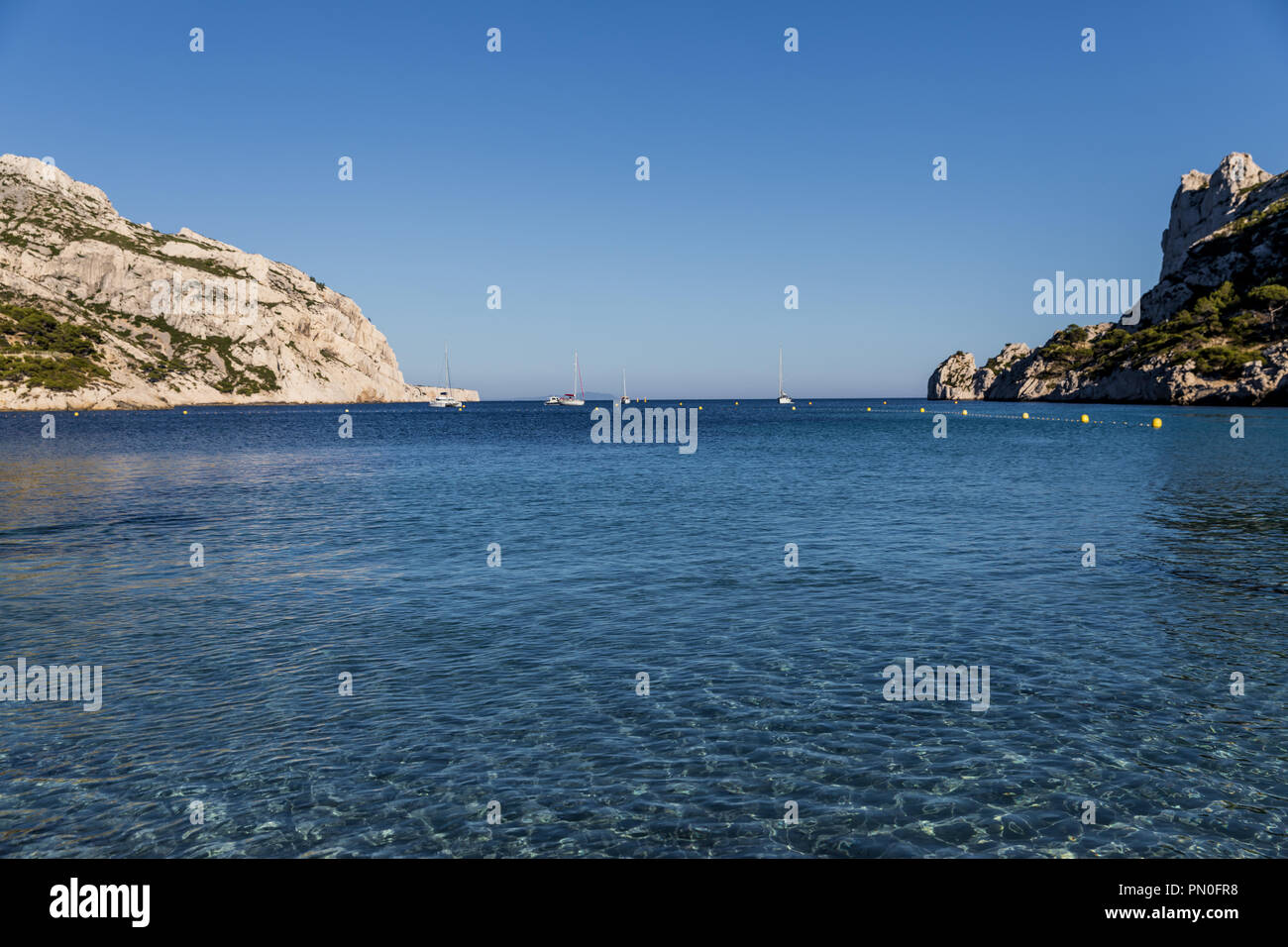 yachts and boats in calm sea harbour and scenic cliffs, Calanques de ...