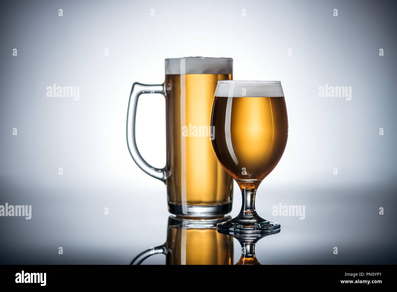 two glasses of tasty beer on reflecting surface, oktoberfest concept ...