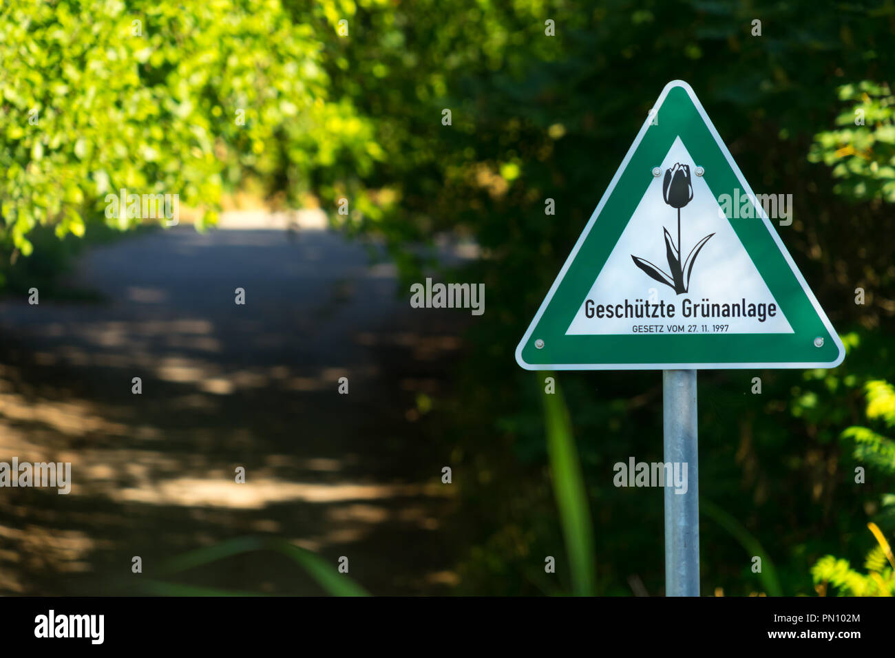 Warning triangular sign with a green border and a flower image in the ...