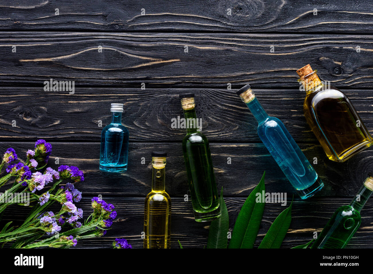 colored bottles of natural herbal essential oils and violet flowers on ...