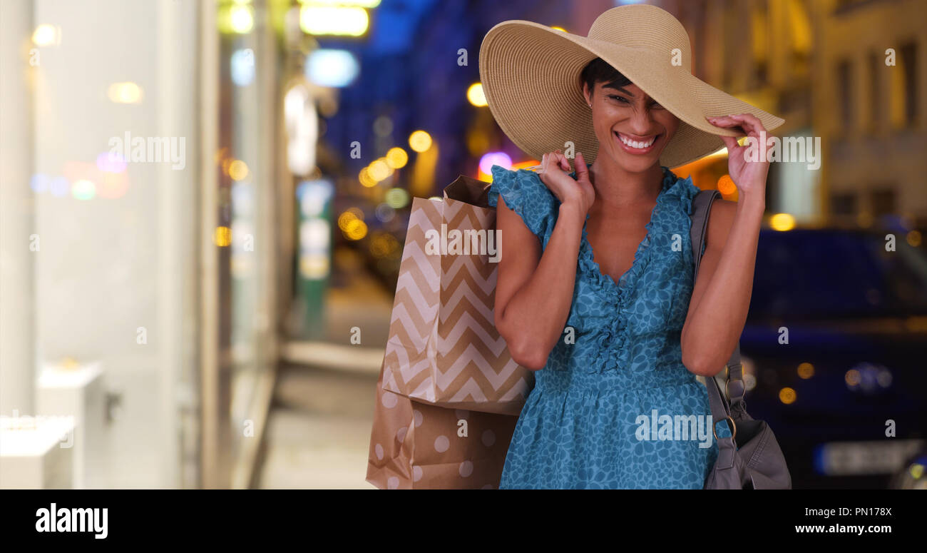 Fashionable black woman posing outside clothes store after shopping ...