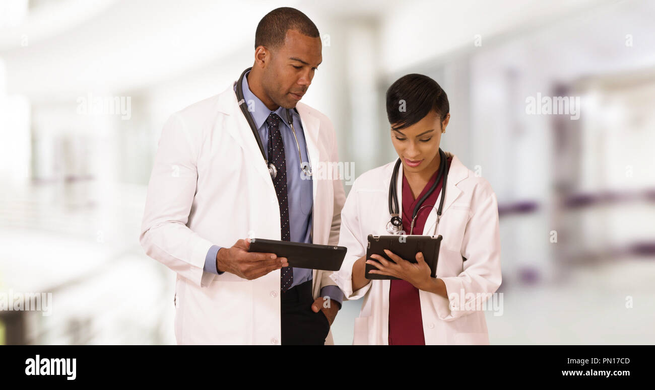 Two professional African American doctors talk while using their ...