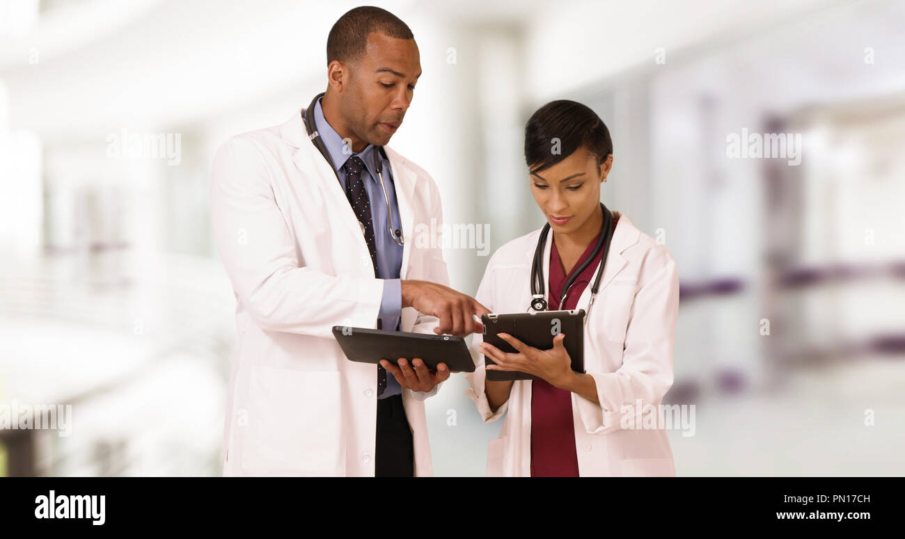 Two professional African American doctors talk while using their ...