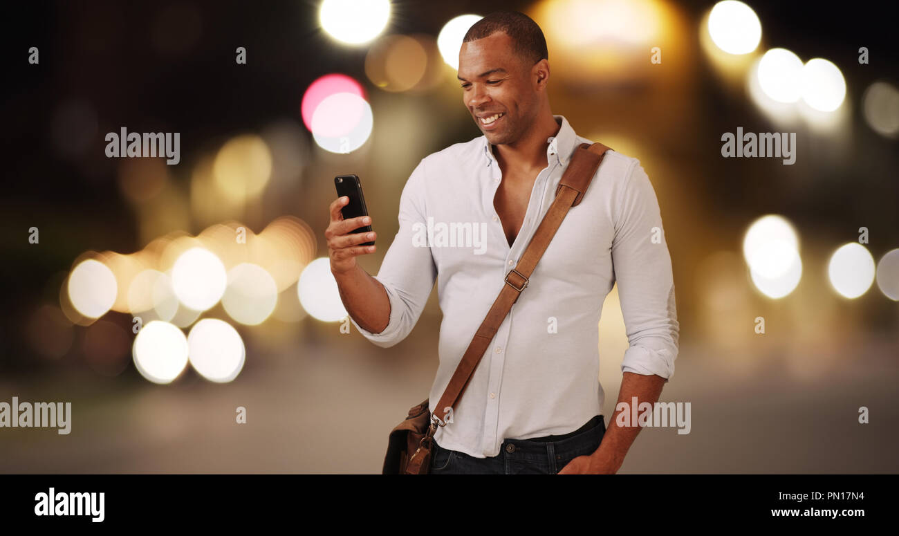 A young black man records video on his mobile phone on a white ...