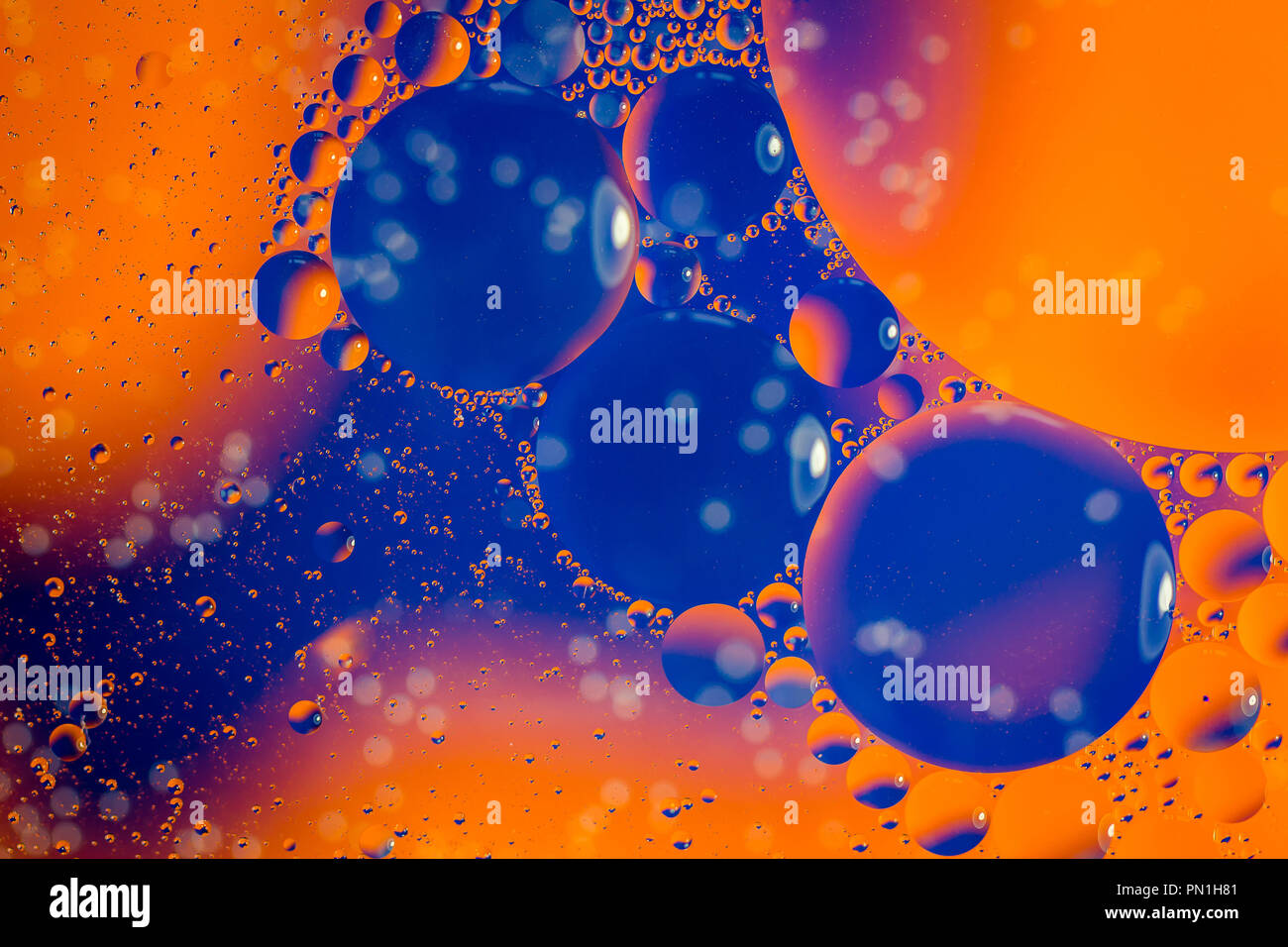 Olive oil dripped into water with colourful paper placed underneath ...