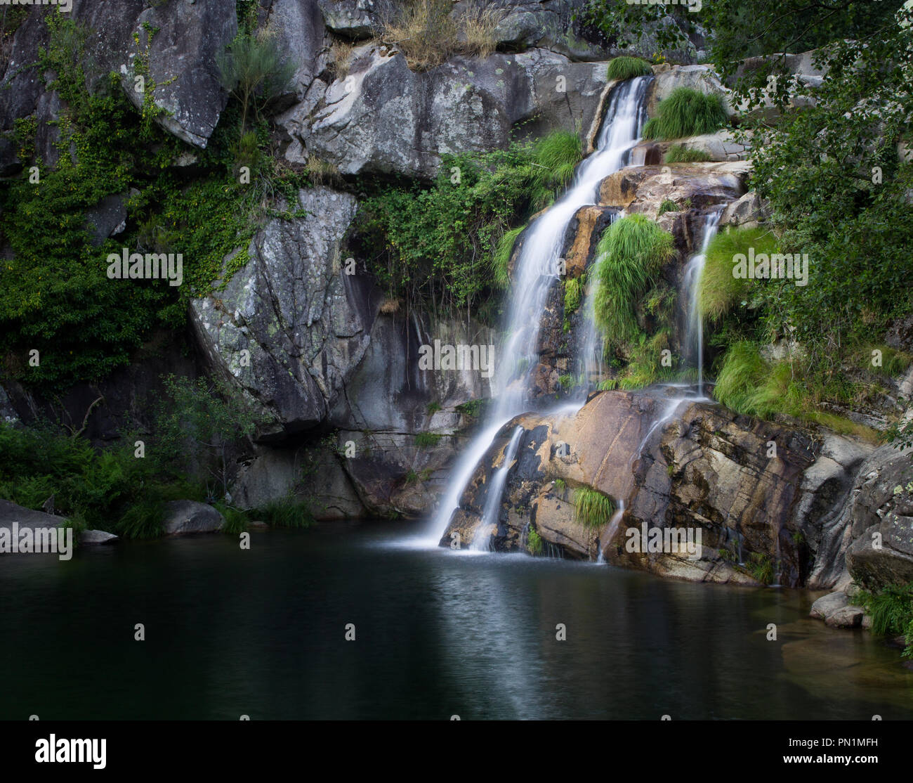 A waterfall ends on a deep dark lake Stock Photo - Alamy