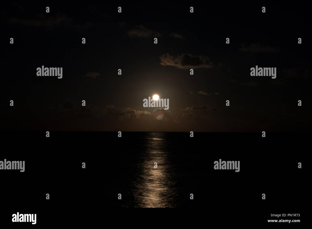 Moon rising over the ocean water Stock Photo - Alamy