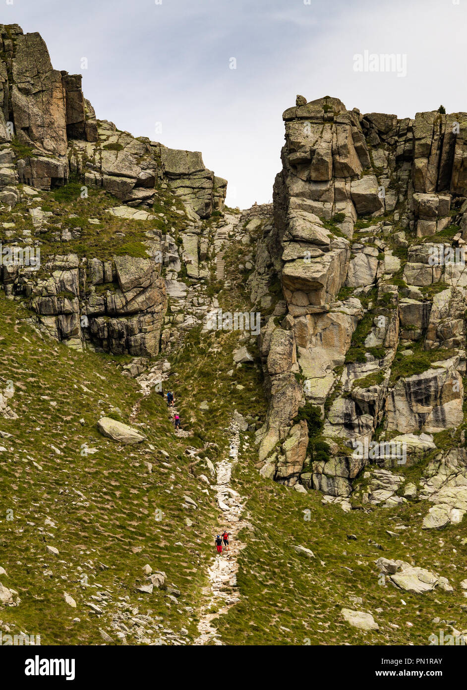 A few hikers climb a steep path between sharp rock formations Stock ...