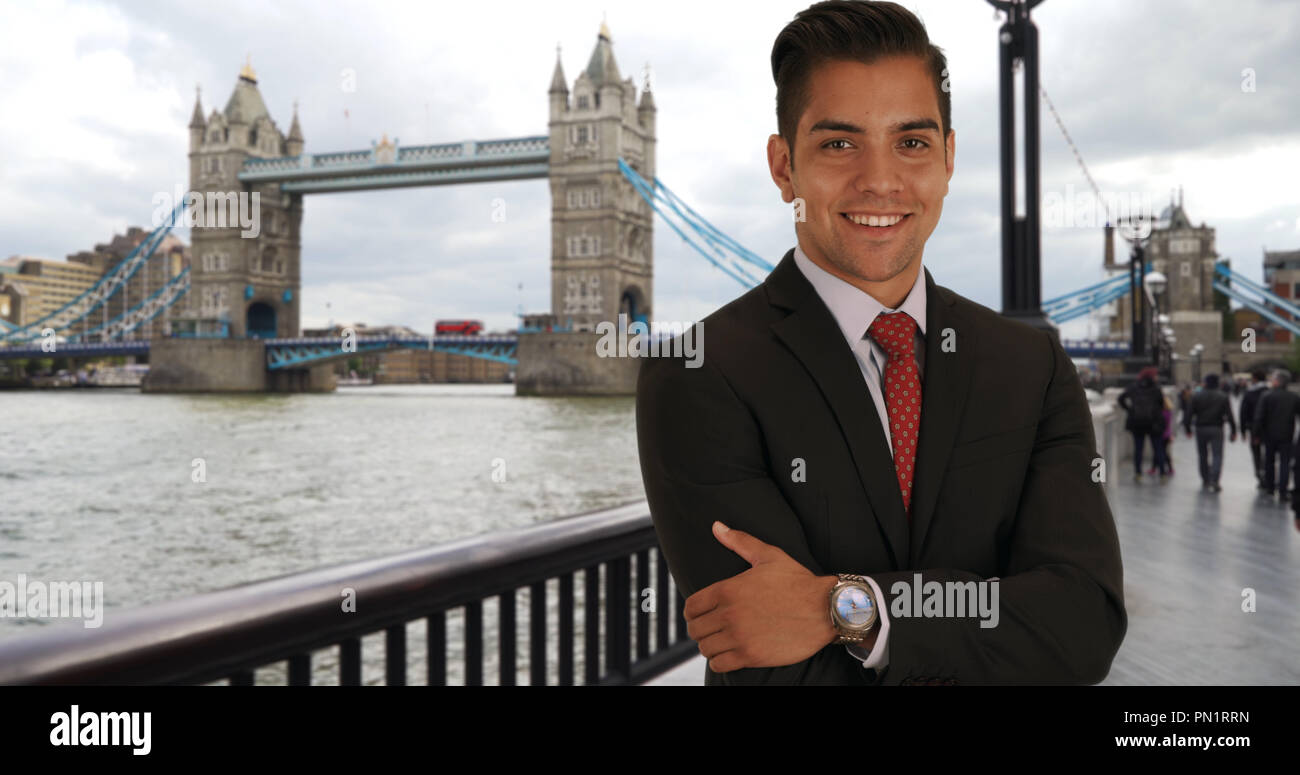 Happy attractive Latino businessman smiling at camera near Tower Bridge ...