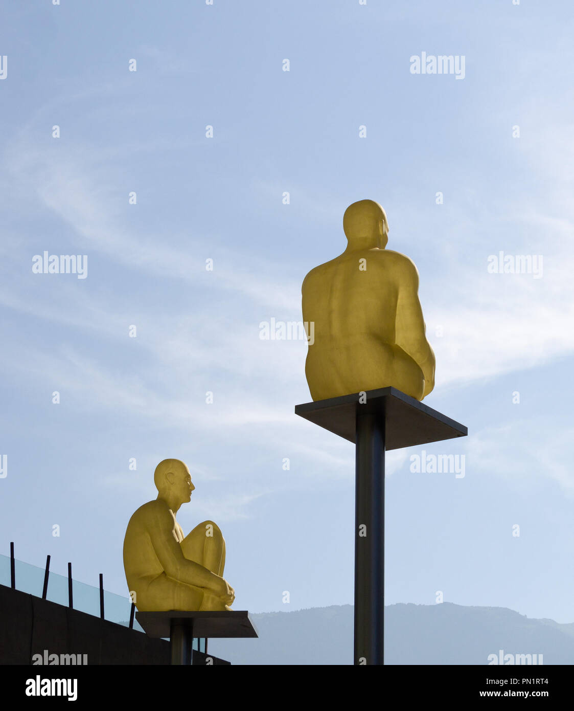 Two sculptures of a golden man sitting Stock Photo - Alamy