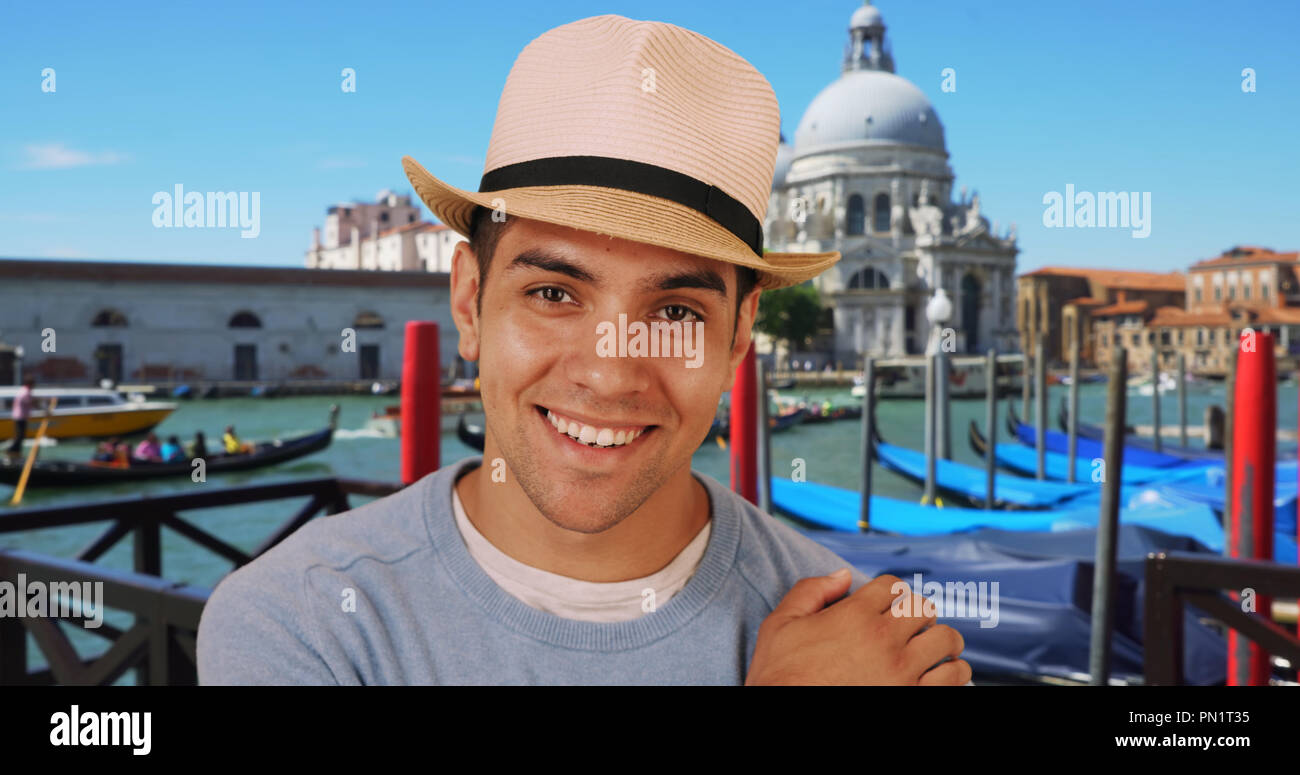 Cute happy Latino male tourist in summer hat smiling at camera by Grand ...