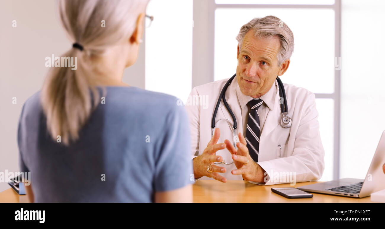 Senior doctor discussing surgery procedure with elderly woman patient ...
