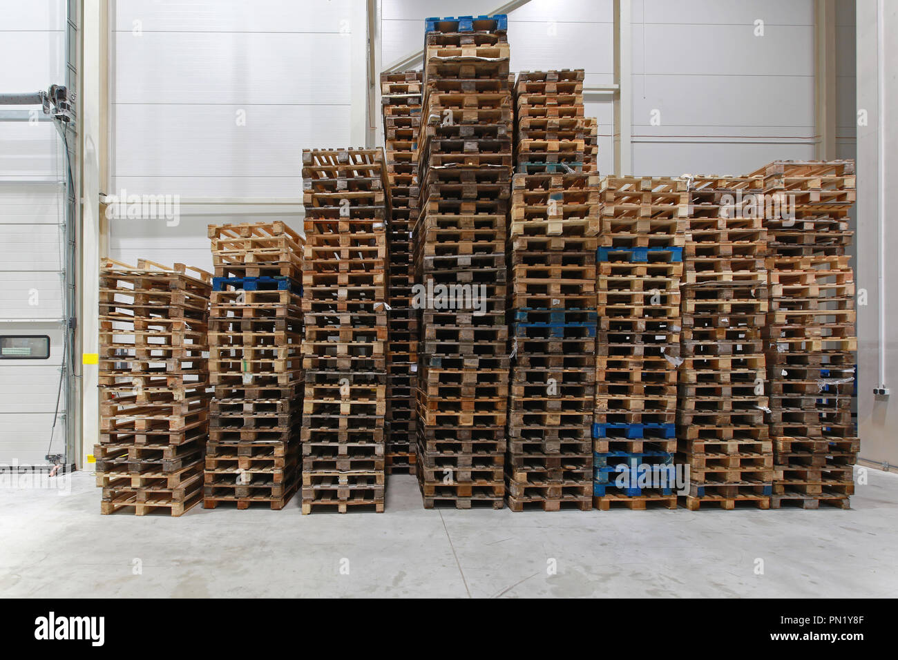 Stack of used wooden pallets in distribution center Stock Photo - Alamy