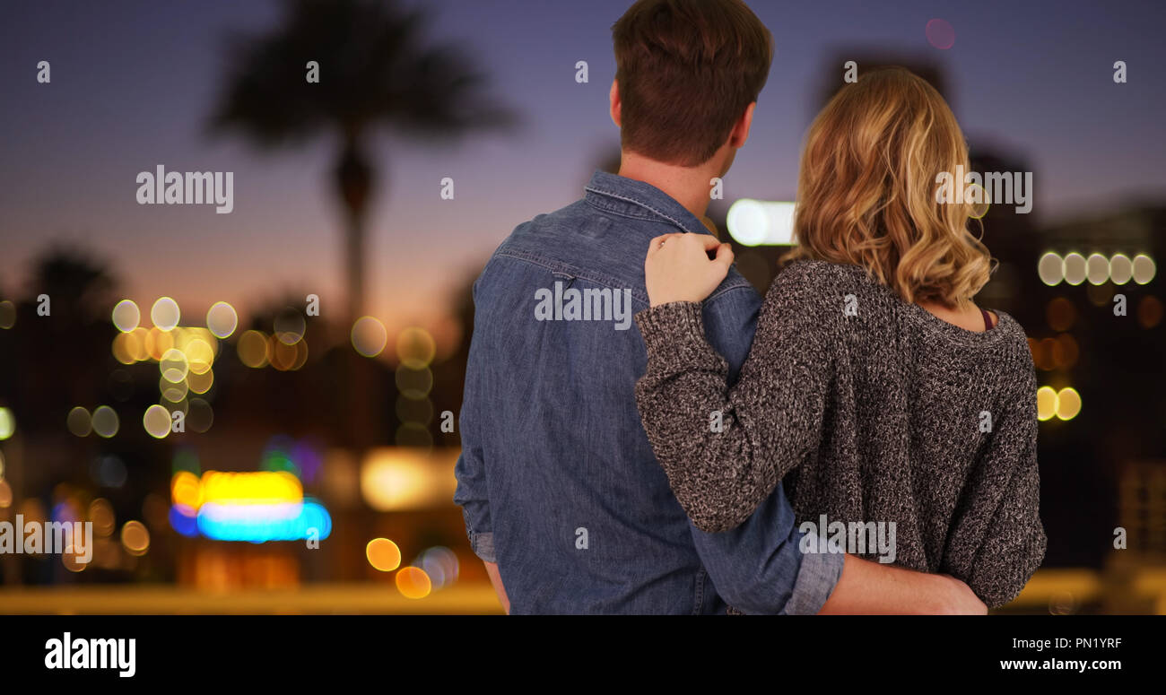 Couple shown from behind embracing and being affectionate downtown ...