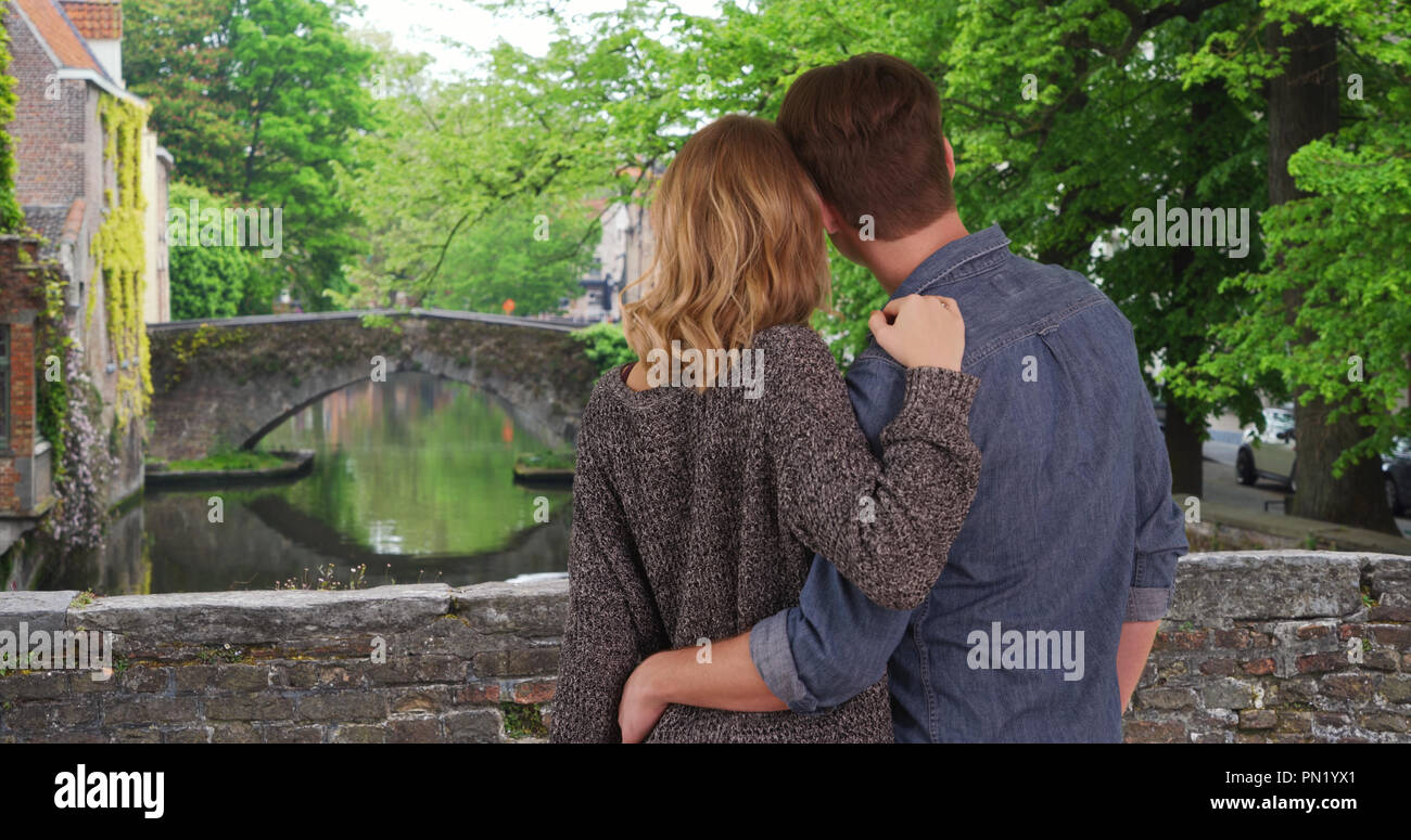Rear view of young married couple looking out at canal smiling Stock ...