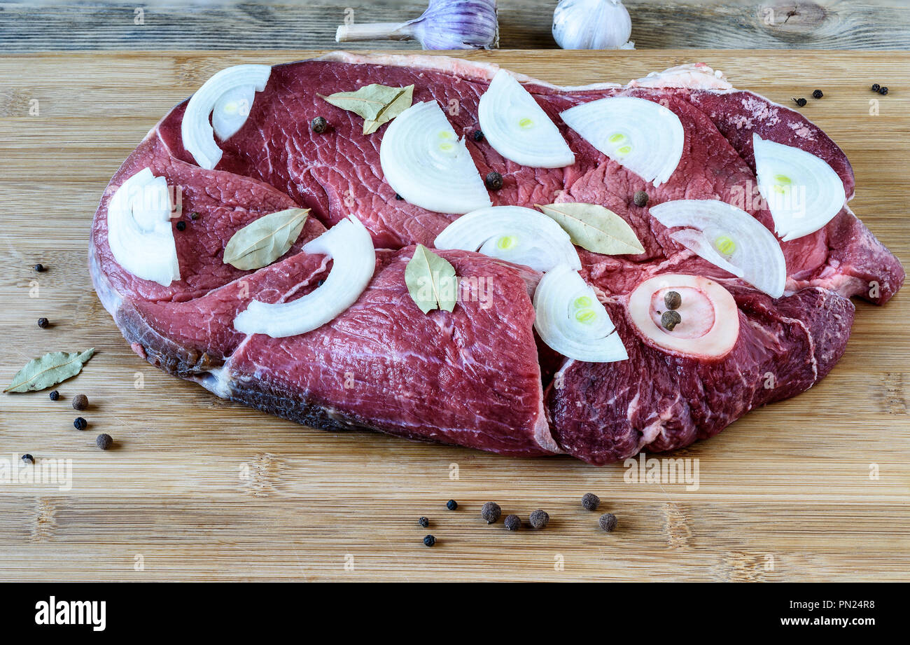 Raw beef meat with laurel leaves, black peppercorns and onion sl Stock ...