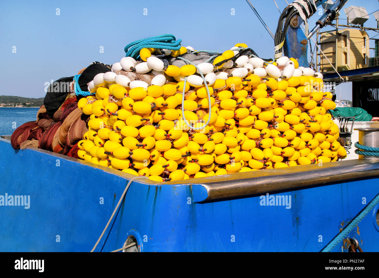 Yellow floats on the pile, covering fishing nets on the blue boat in ...