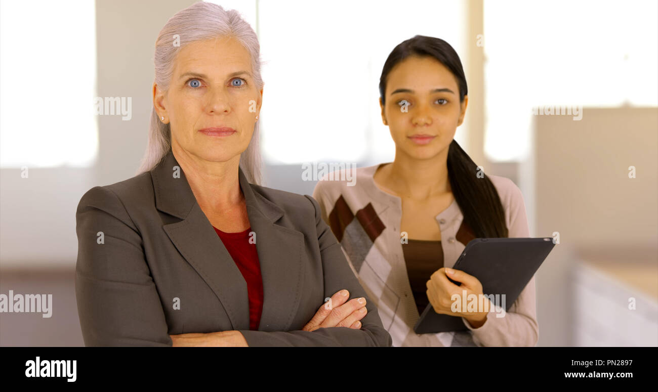 A business executive and her secretary pose for a portrait at work ...