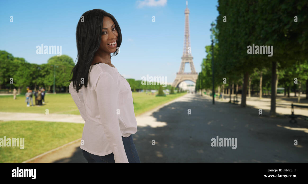 Youthful pretty African-American female near Eiffel Tower in Paris ...