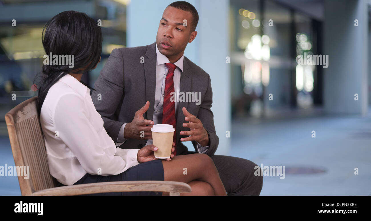 Businessman and businesswoman having serious conversation on park bench ...