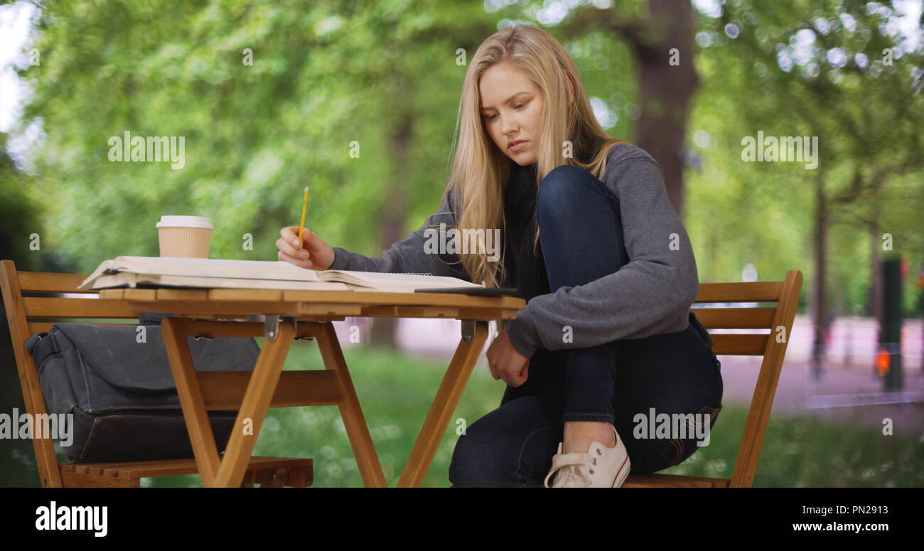 Female Caucasian student in park stresses over difficult class material ...