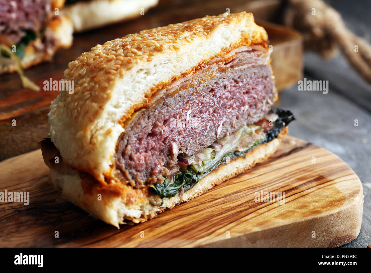 Cut in half angus burger on grain bun with tomato relish, lettuce and ...