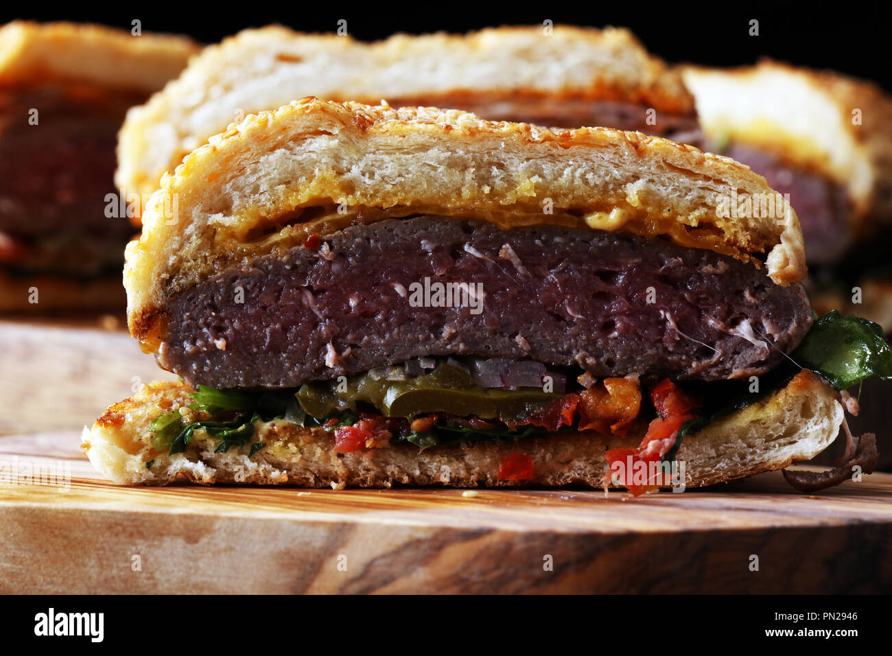 Cut in half angus burger on grain bun with tomato relish, lettuce and ...