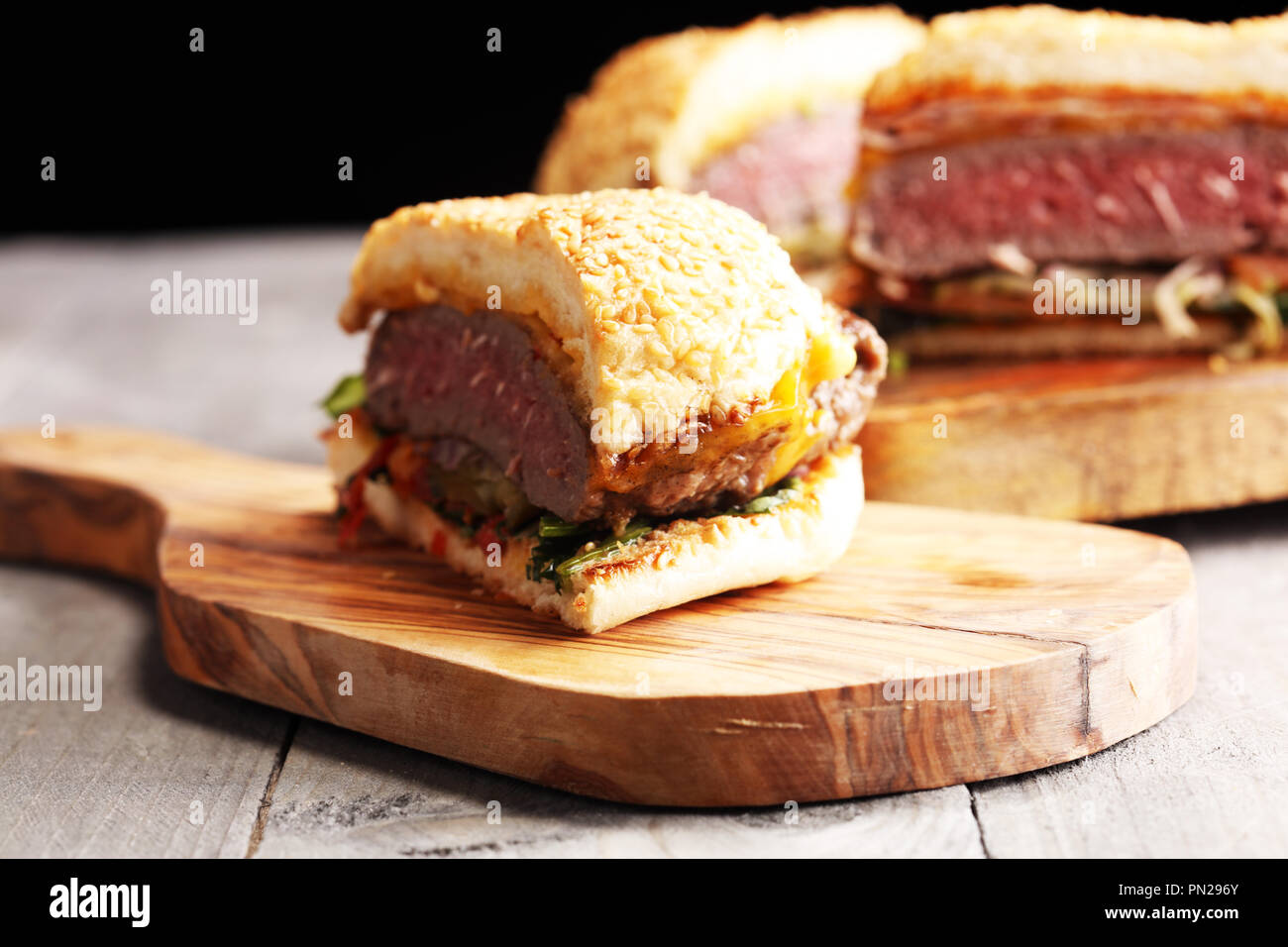 Cut in half angus burger on grain bun with tomato relish, lettuce and ...