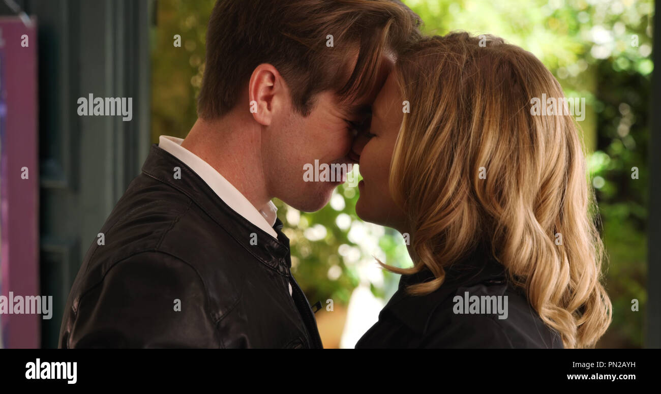 Happy millennial couple stealing a kiss outdoors Stock Photo - Alamy
